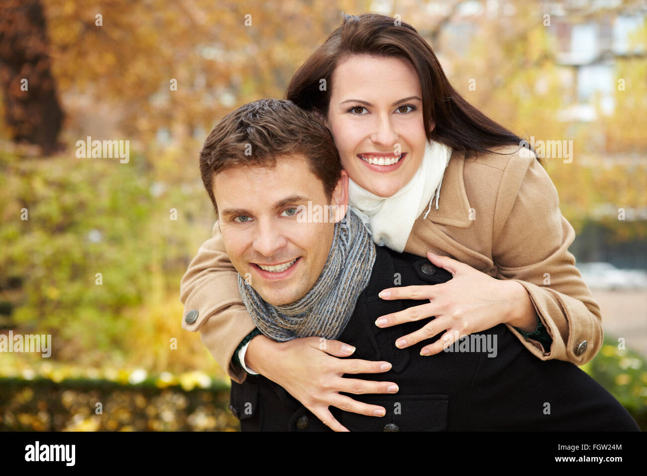 Happy man giving attractive woman piggyback ride in fall Stock Photo ...