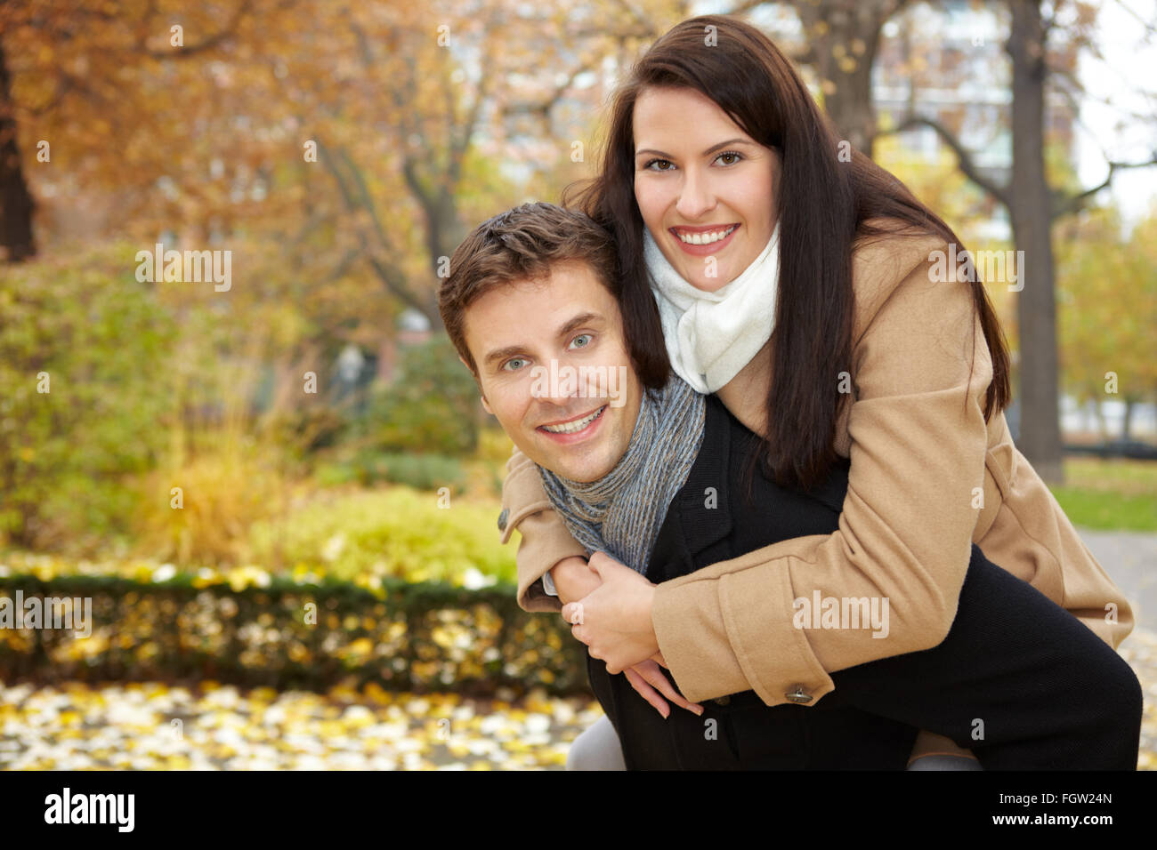 Happy couple doing a piggyback ride in a fall park Stock Photo - Alamy