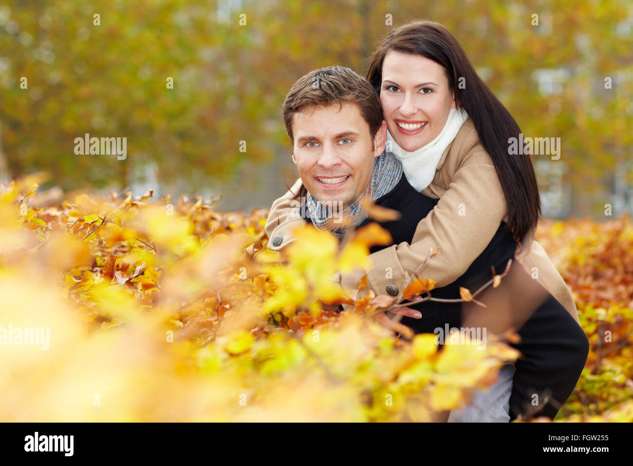 Happy man carrying smiling woman piggyback in fall Stock Photo - Alamy