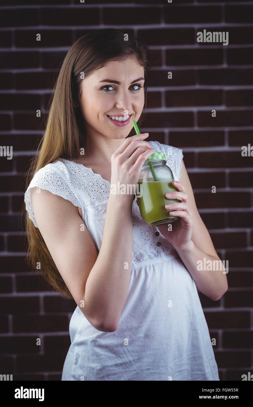 Pretty woman sipping on green juice Stock Photo - Alamy