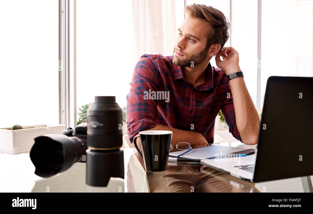 Entrepreneurial photographer looking off camera at his desk Stock Photo ...