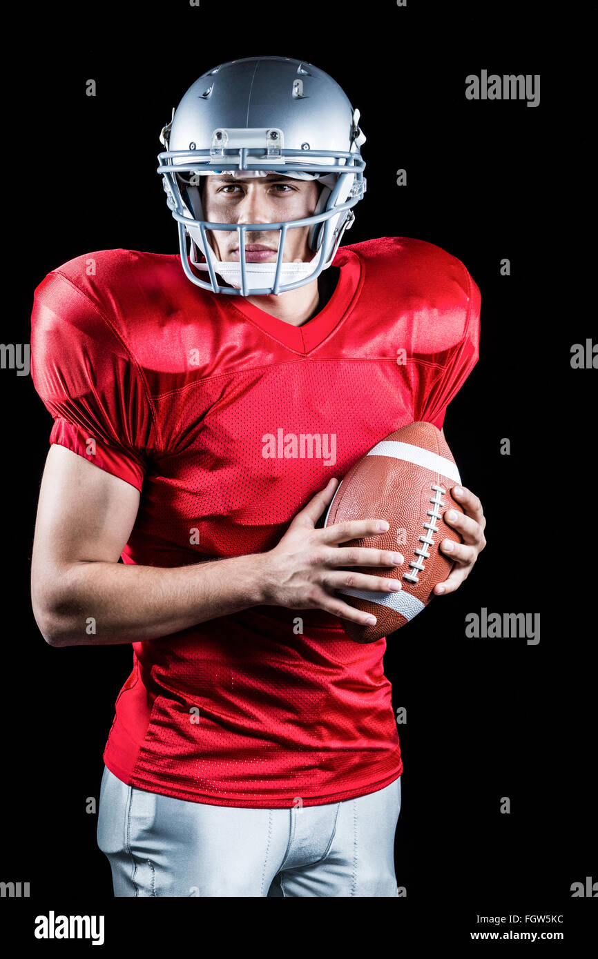 Confident American football player holding ball Stock Photo - Alamy