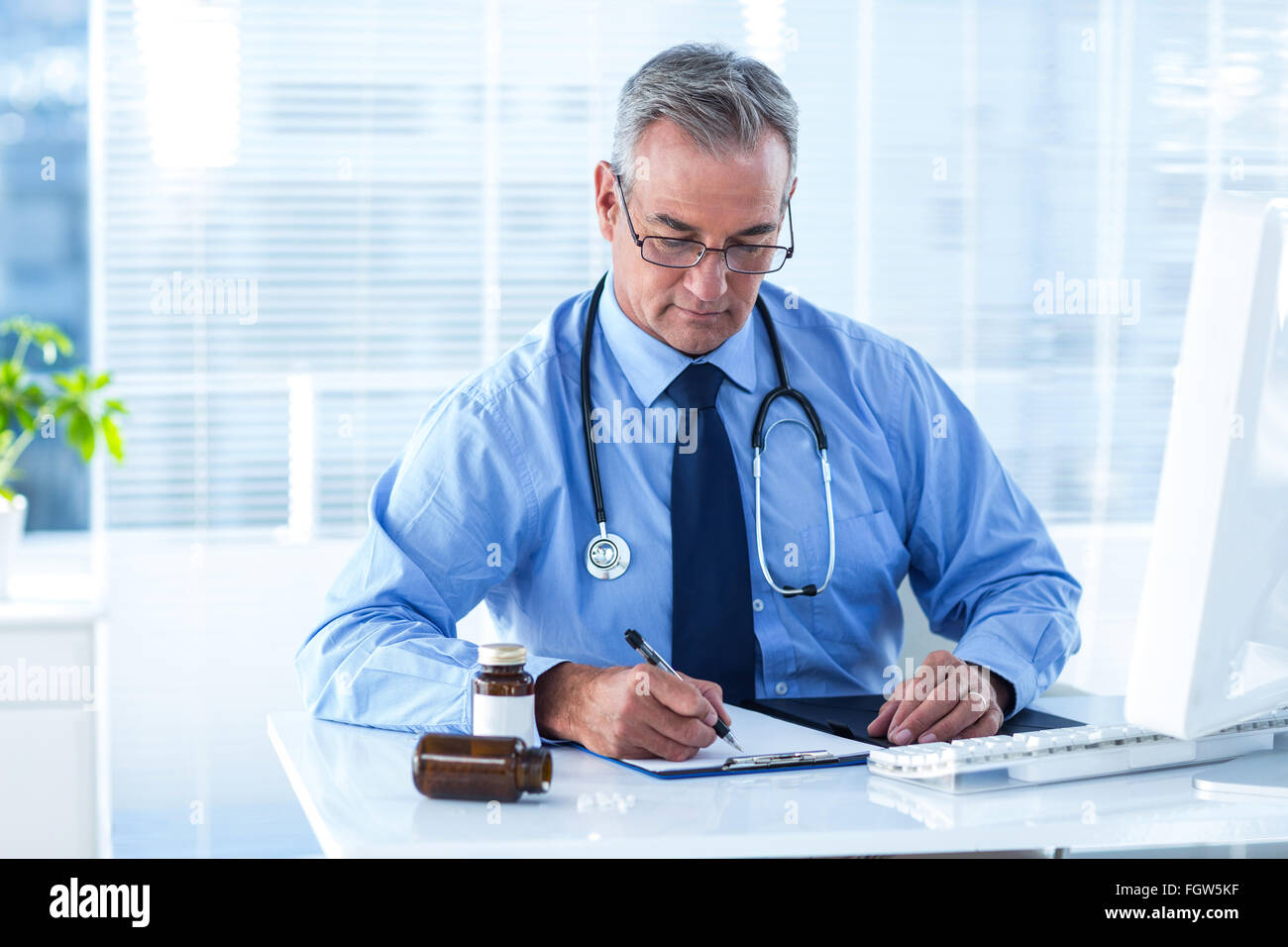 Male doctor writing prescription in hospital Stock Photo - Alamy