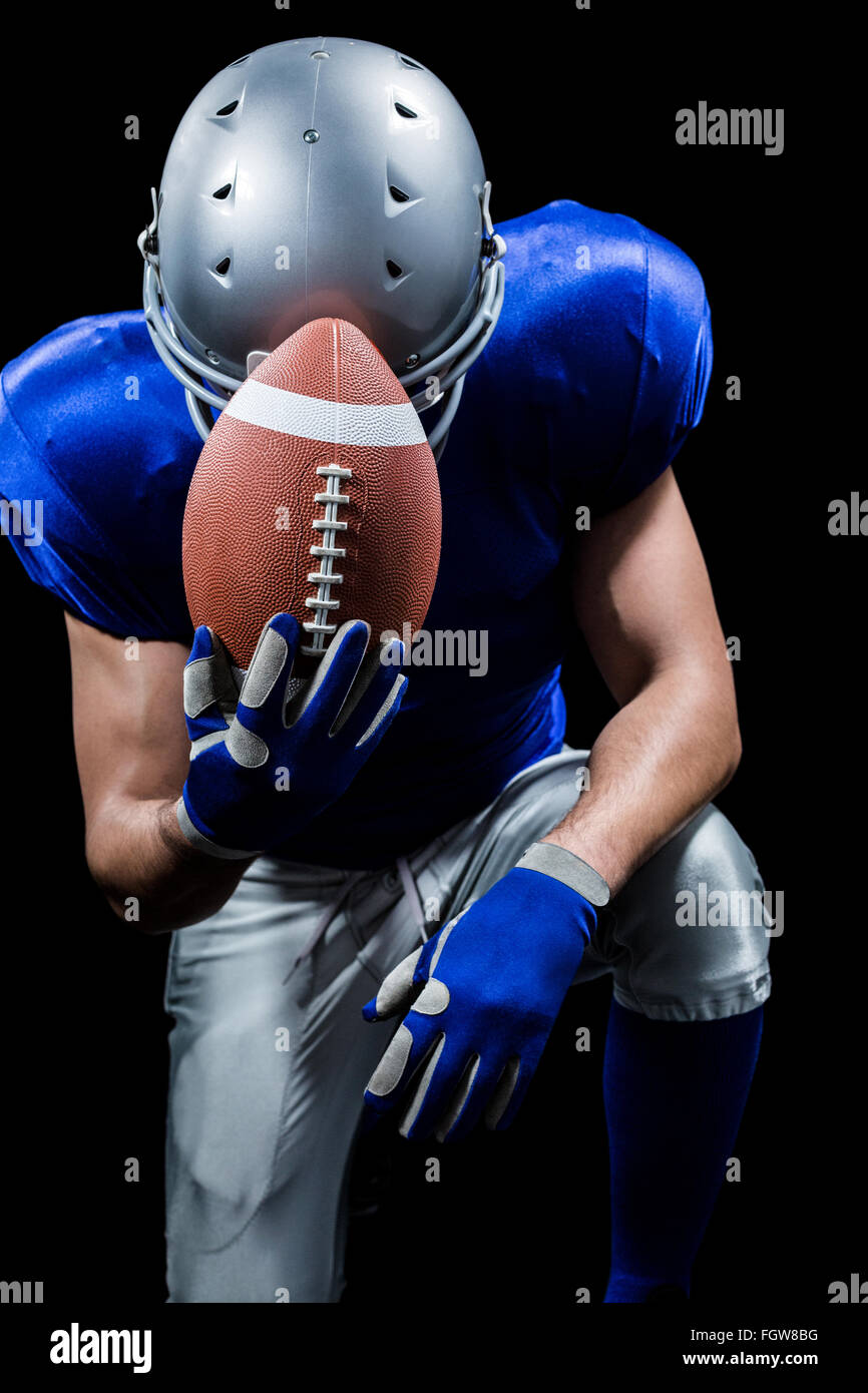 Upset American football player kneeling while holding ball Stock Photo ...
