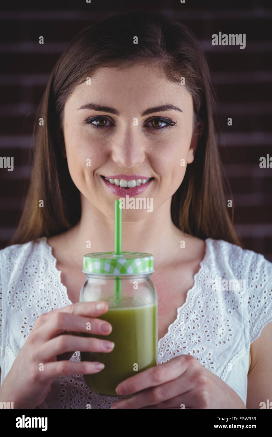 Pretty woman sipping on green juice Stock Photo - Alamy