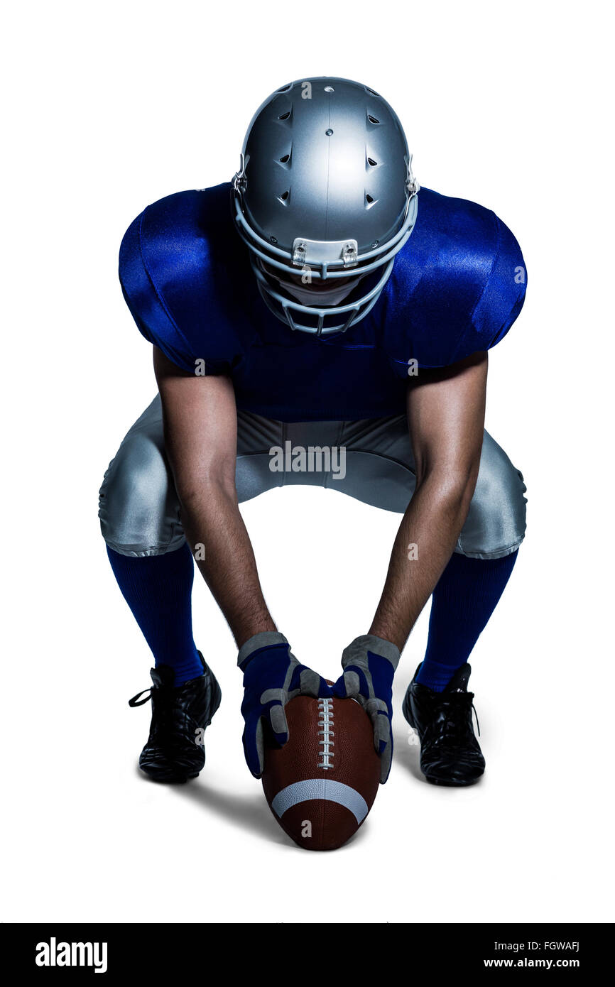 American football player in uniform holding ball while crouching Stock ...