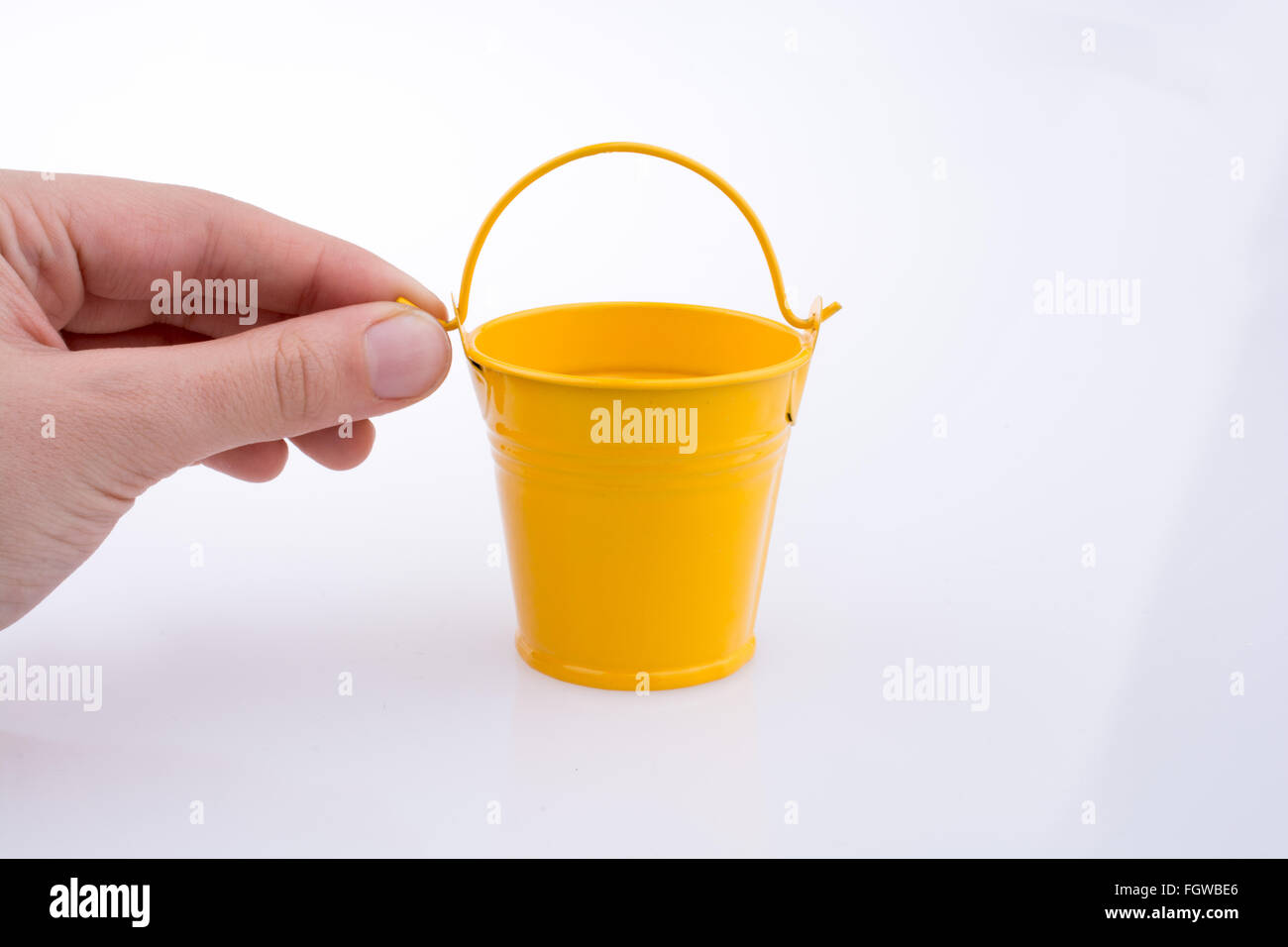 Hand holding a yellow bucket on a white background Stock Photo - Alamy