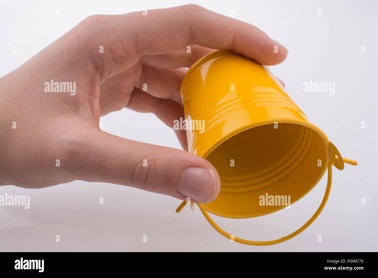 Hand holding a yellow bucket on a white background Stock Photo - Alamy