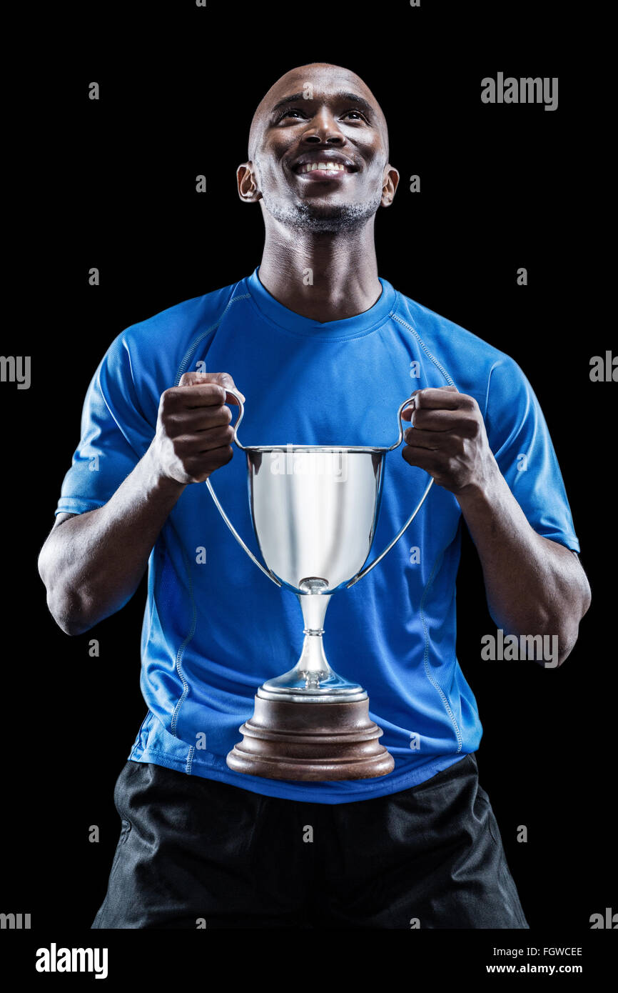 Happy athlete holding trophy looking up Stock Photo - Alamy
