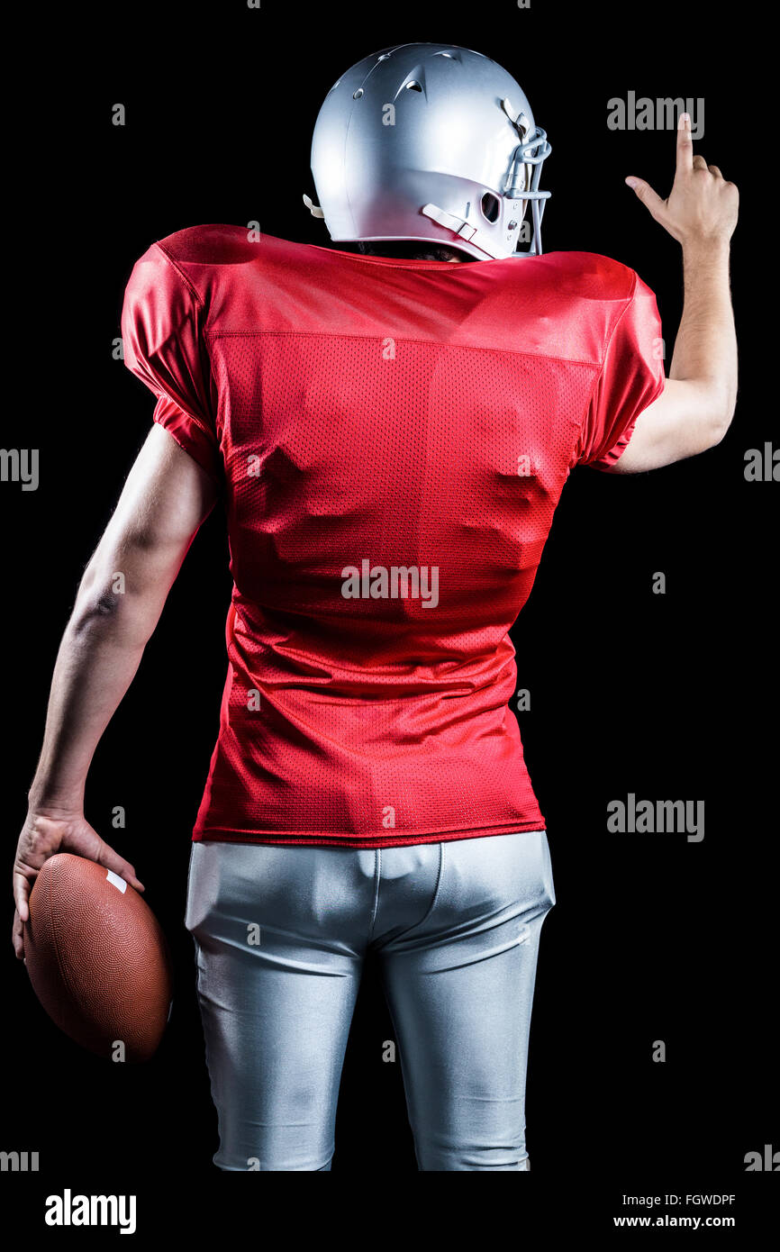 Rear view of American football player pointing while holding ball Stock ...