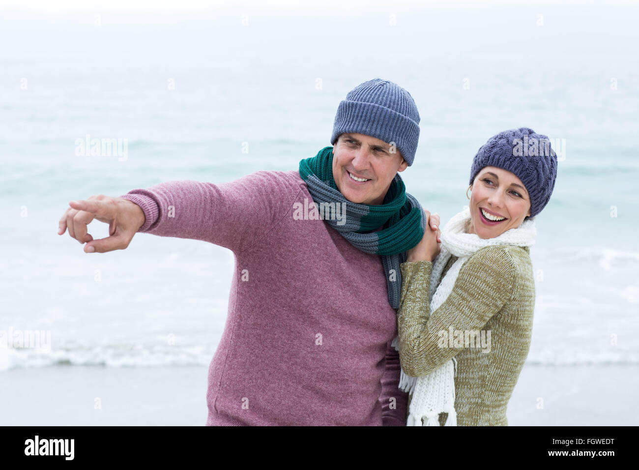Smiling happy couple pointing towards something Stock Photo - Alamy