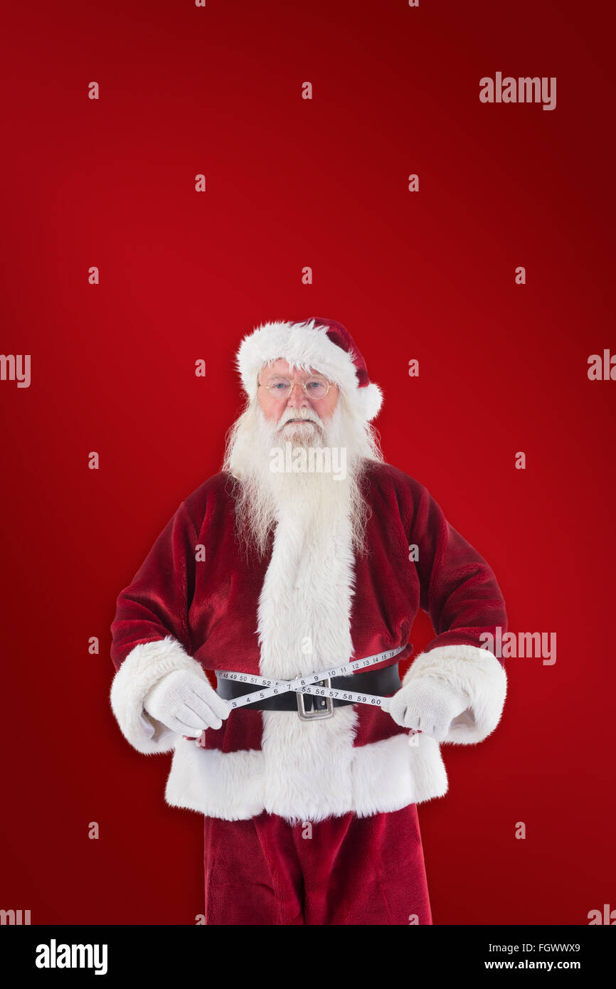 Composite image of santa claus measures his belly Stock Photo - Alamy