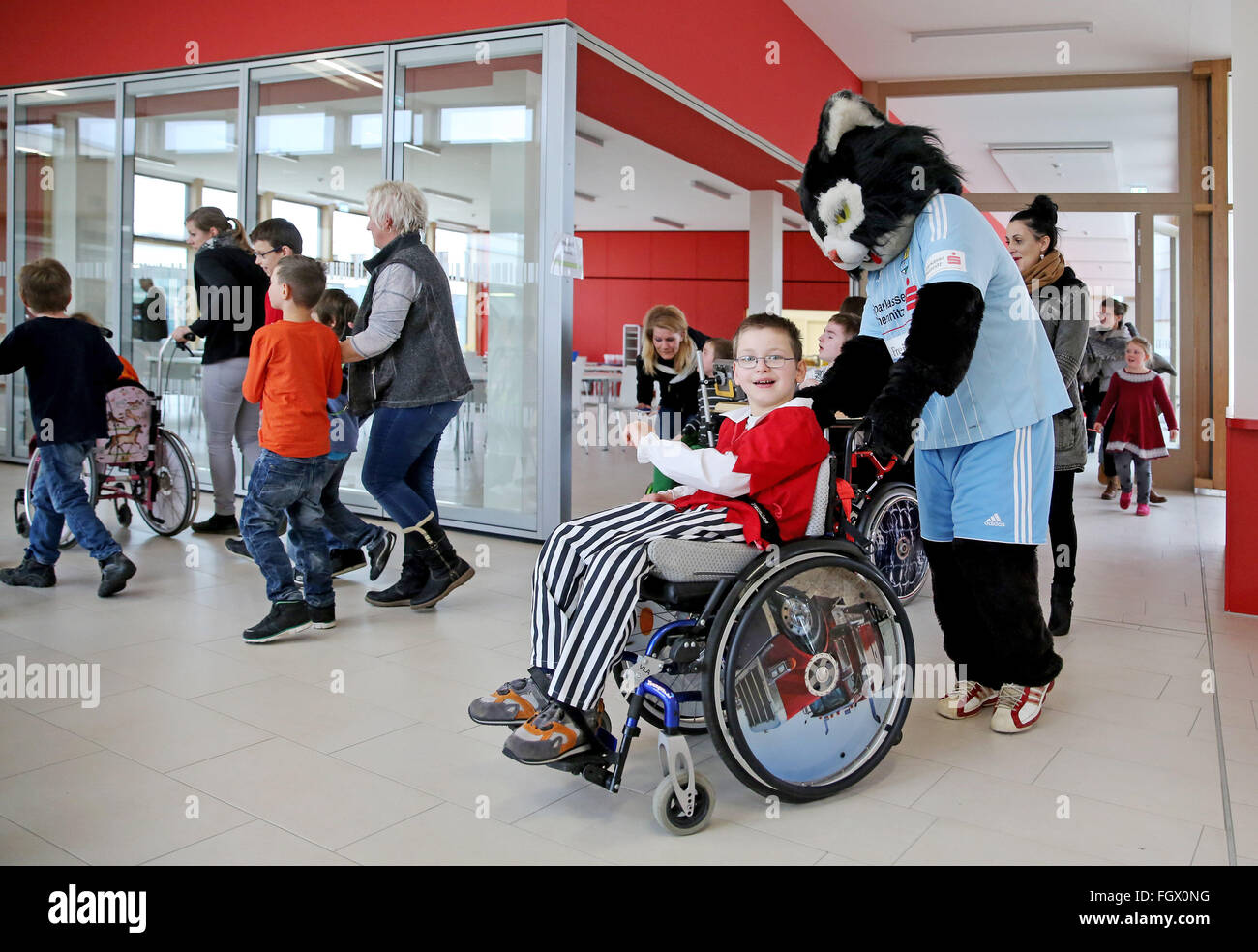 Chemcat, the mascot of Chemnitz FC, pushes the wheelchair of a boy ...