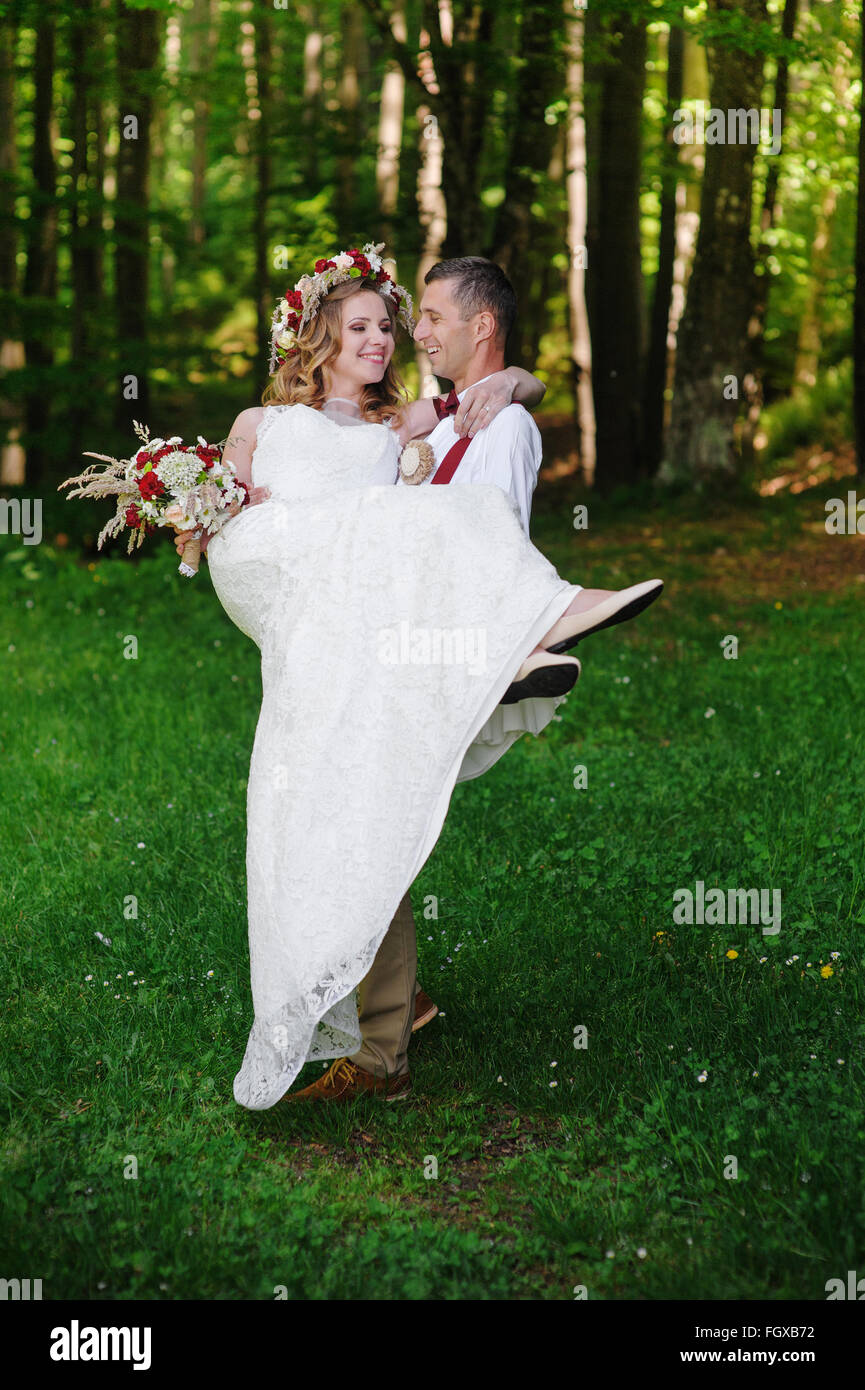 Young groom carrying his beautiful wife in park Stock Photo - Alamy