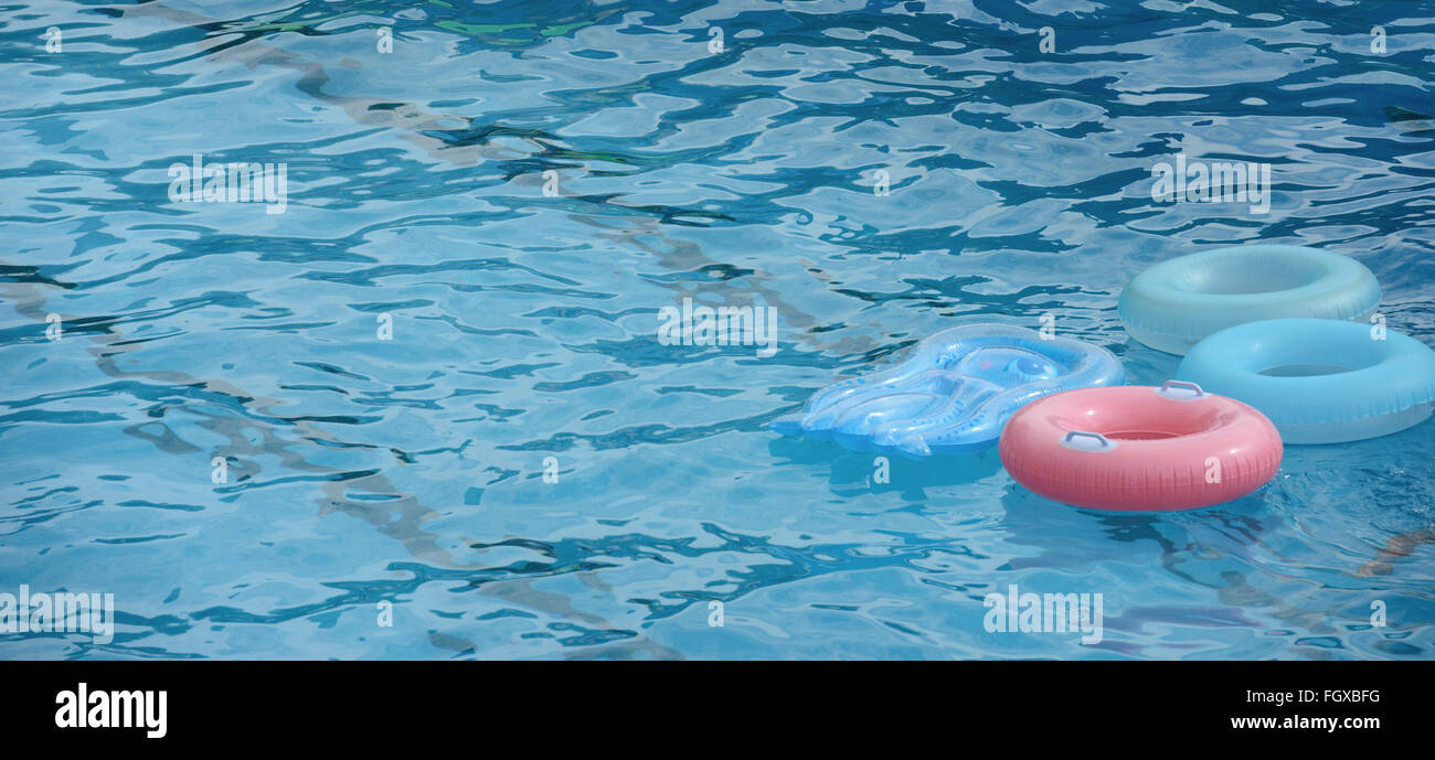 Inflatable pink and blue float rings for swimming are floating in blue ...
