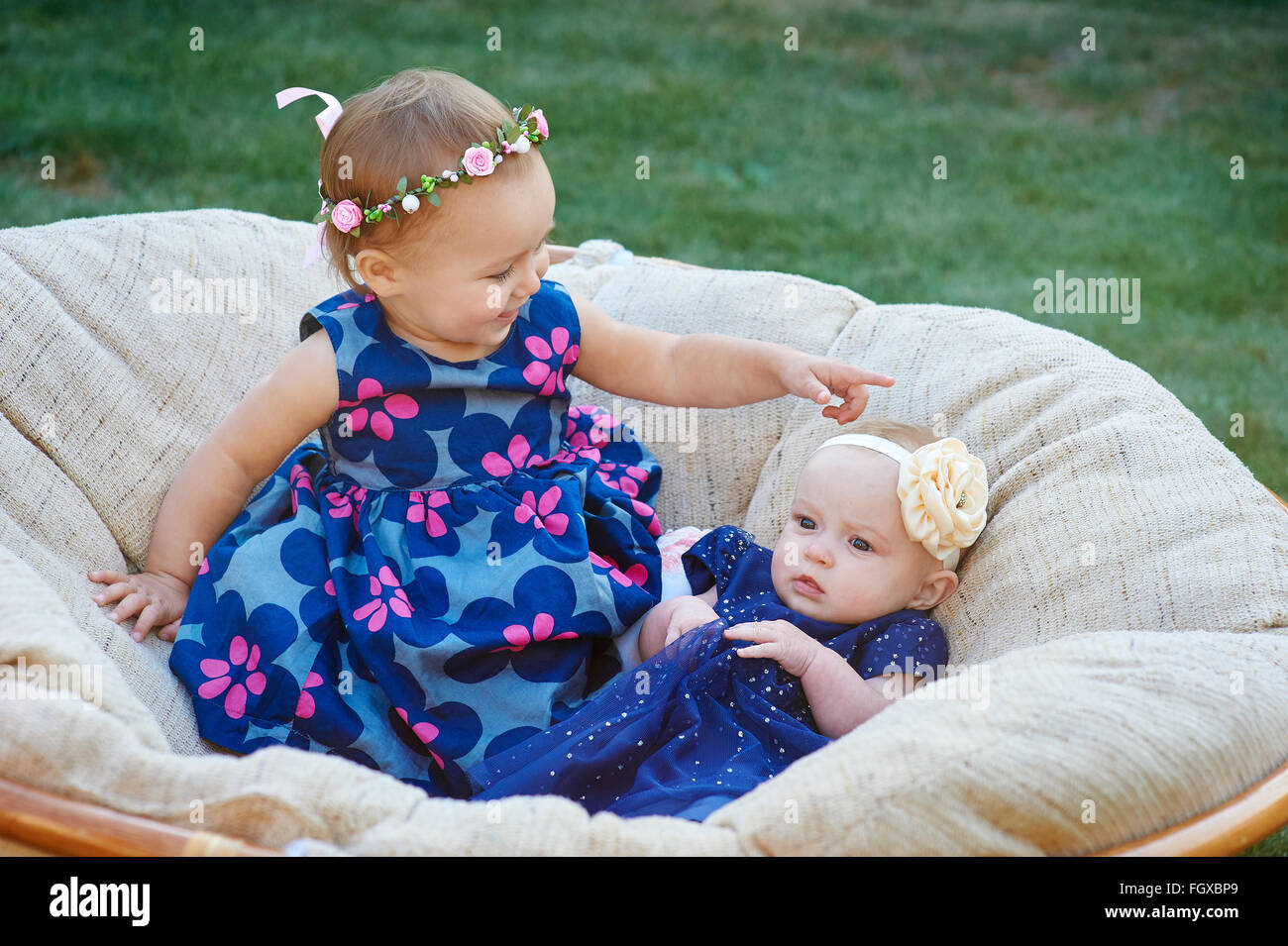 Two funny kids sitting in the soft light chair together in spring park ...