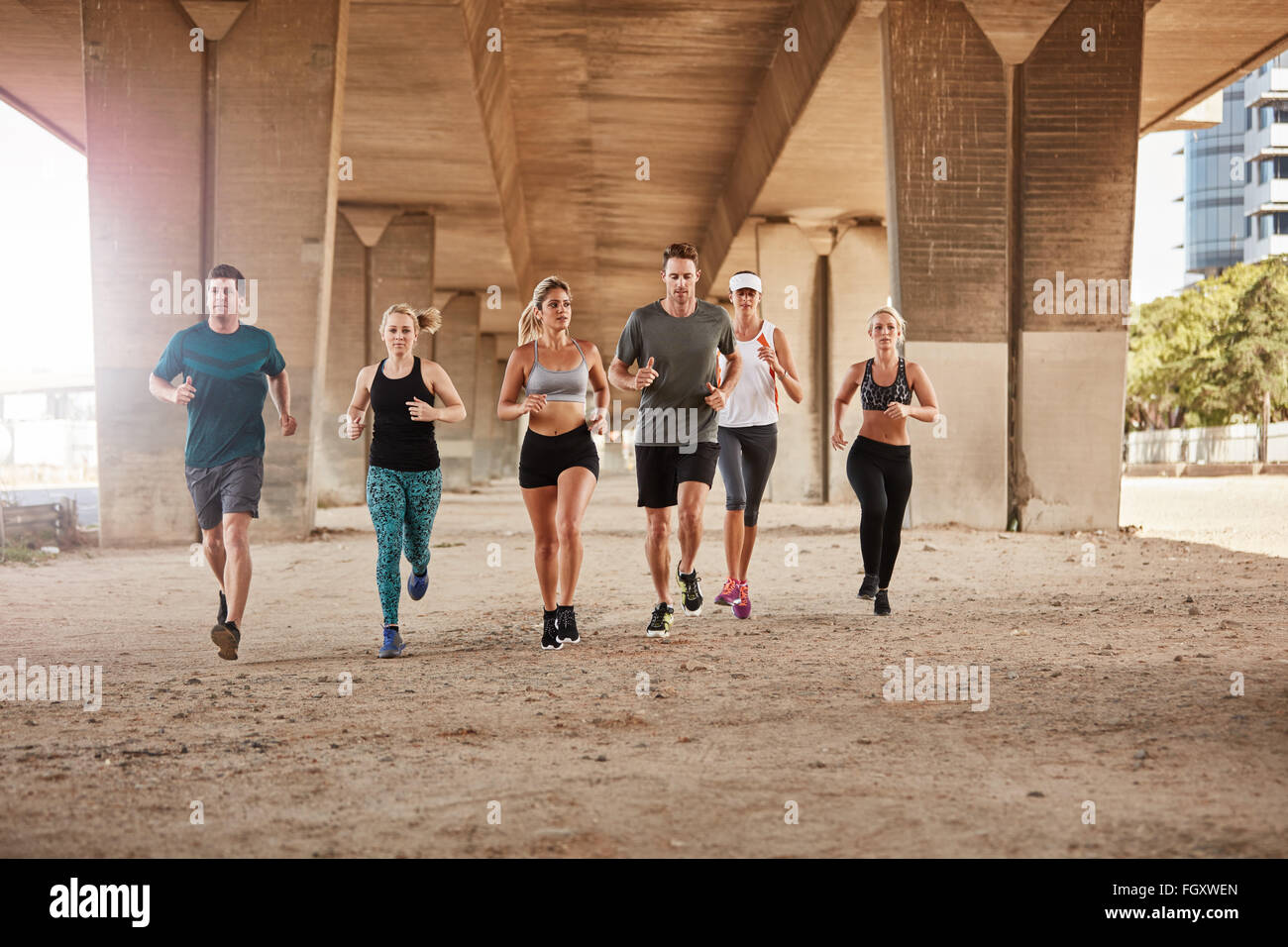 Portrait of group of healthy young people running together in city ...