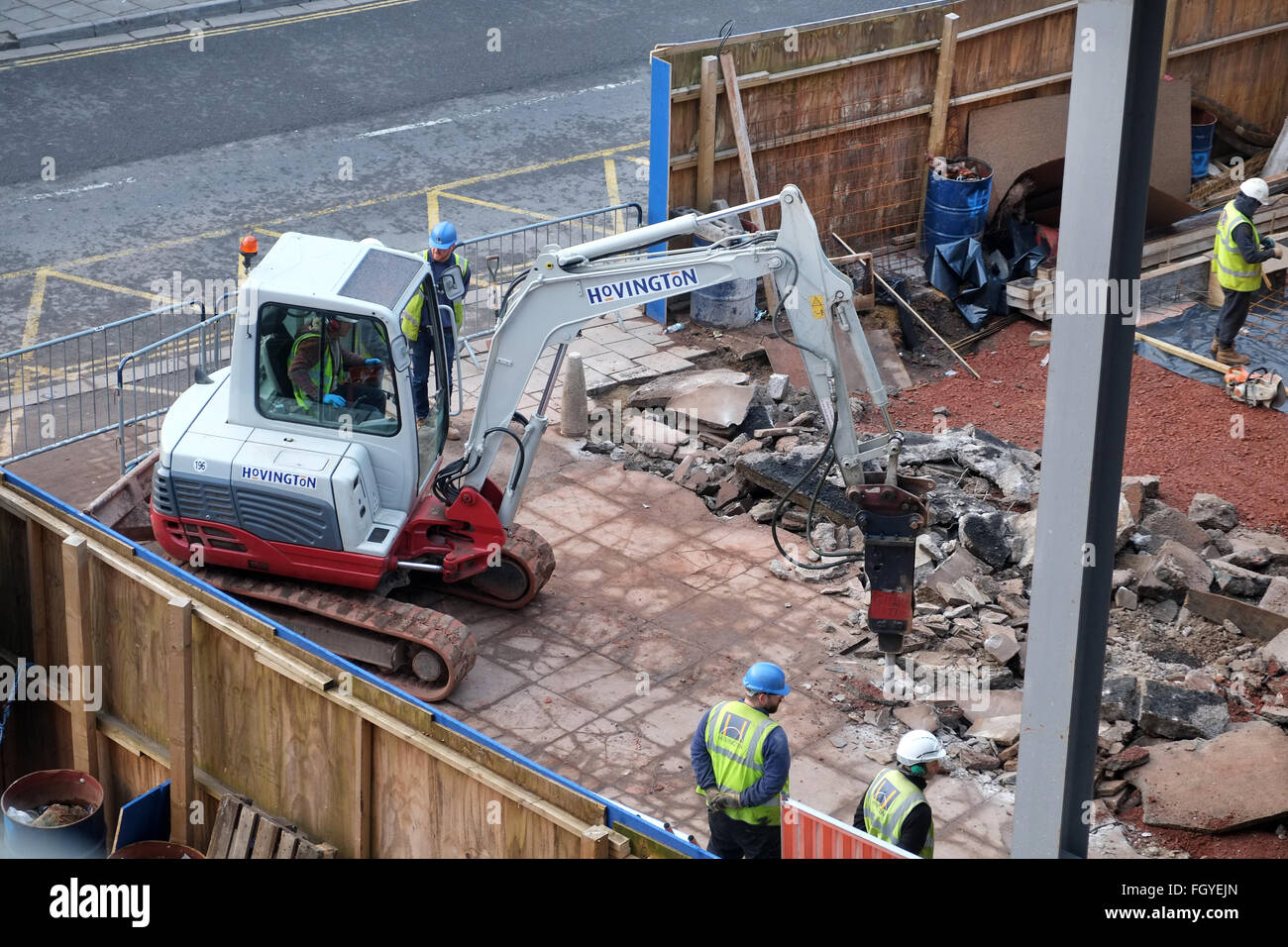Small digger with a concrete demolition breaker working on a ...
