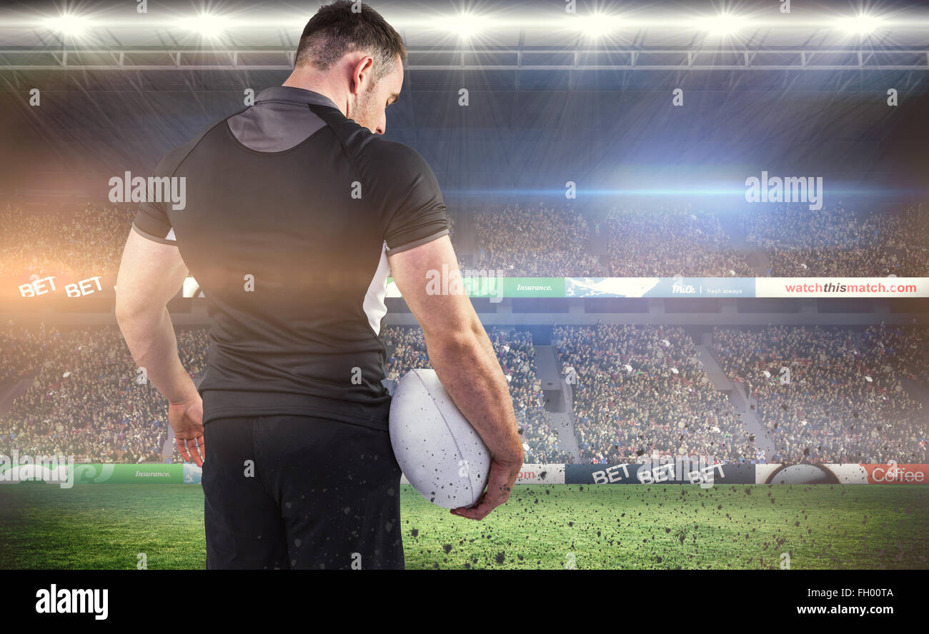 Composite image of tough rugby player holding ball Stock Photo - Alamy