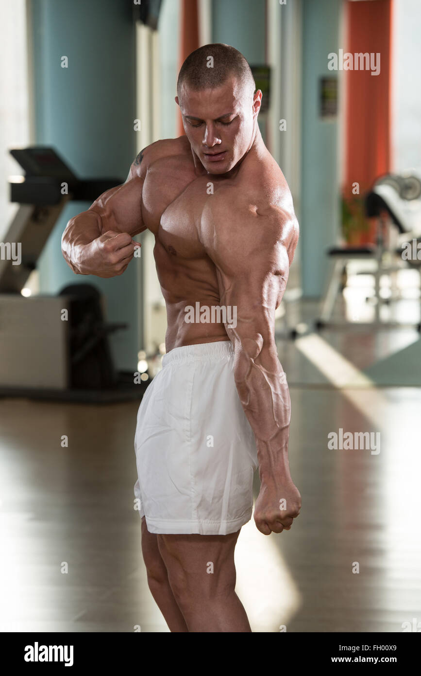 Serious Man Standing In The Gym And Flexing Muscles Stock Photo - Alamy