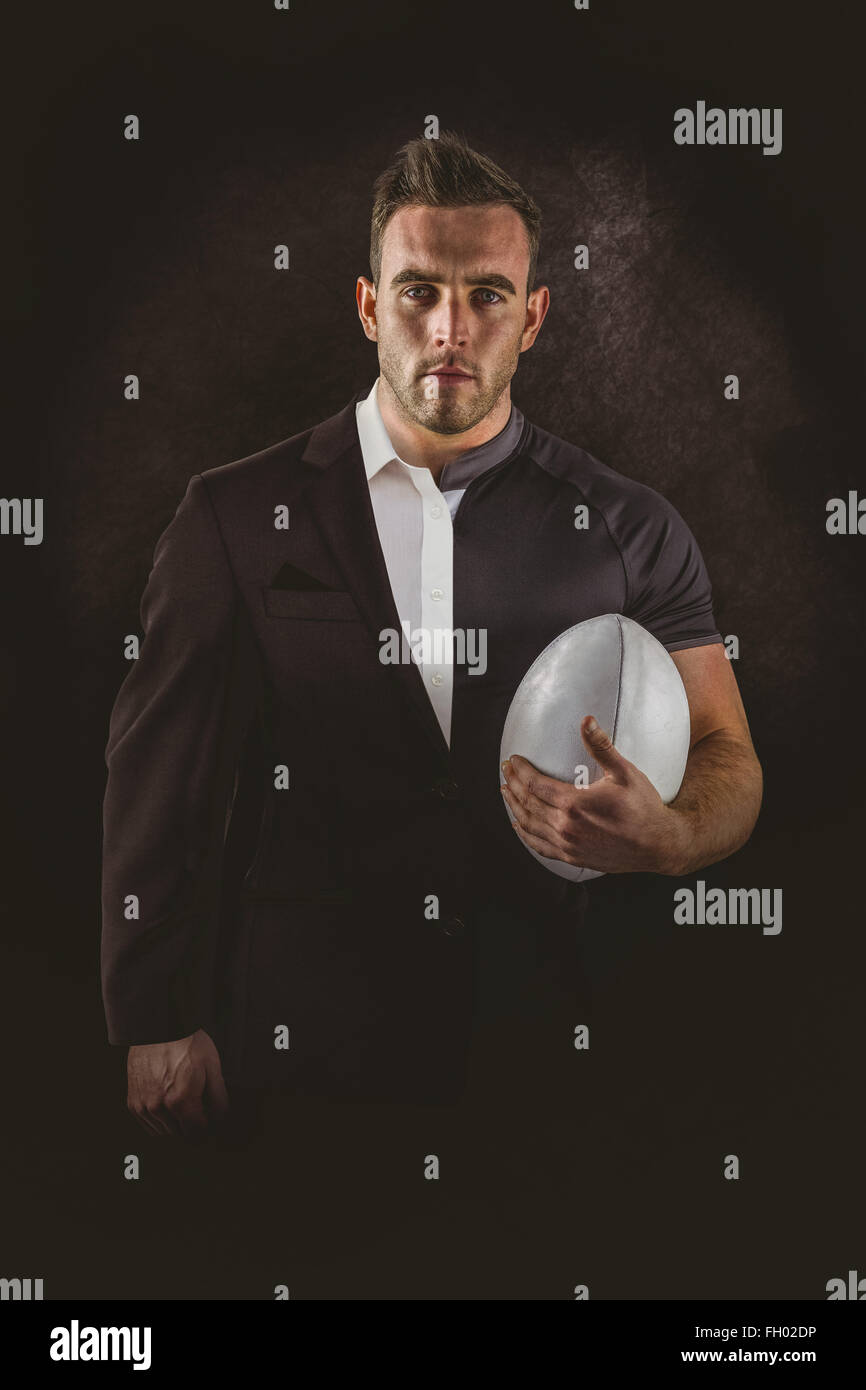Composite image of tough rugby player holding ball Stock Photo - Alamy