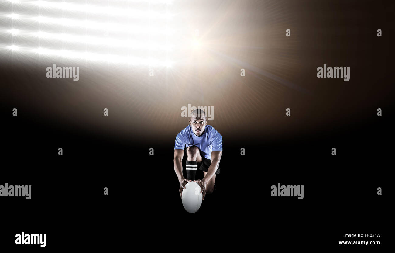 Composite image of portrait of rugby player kneeling and holding ball ...