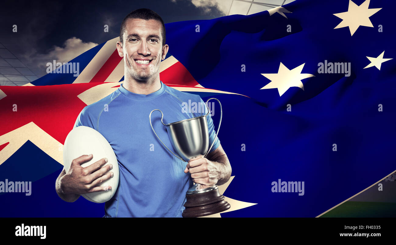 Composite image of portrait of smiling rugby player holding trophy and ...