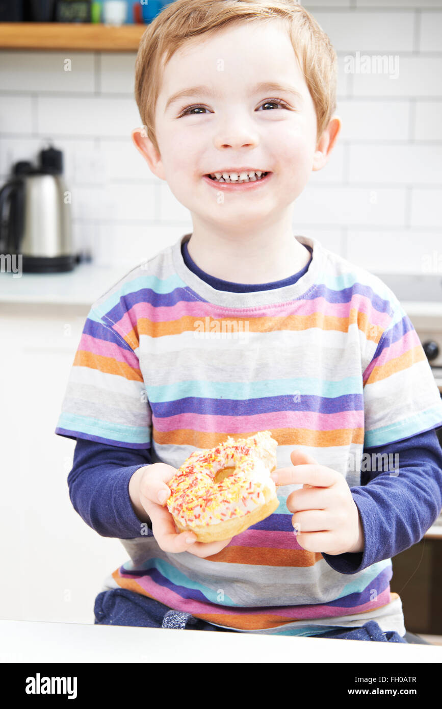 Young Boy Eating Sugary Donut For Snack Stock Photo - Alamy