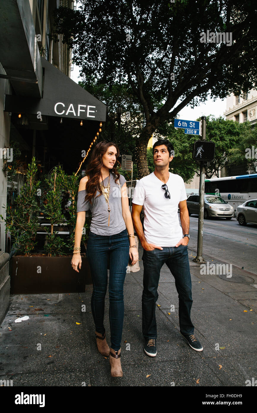 A young couple walk down the street in downtown Los Angeles, California ...