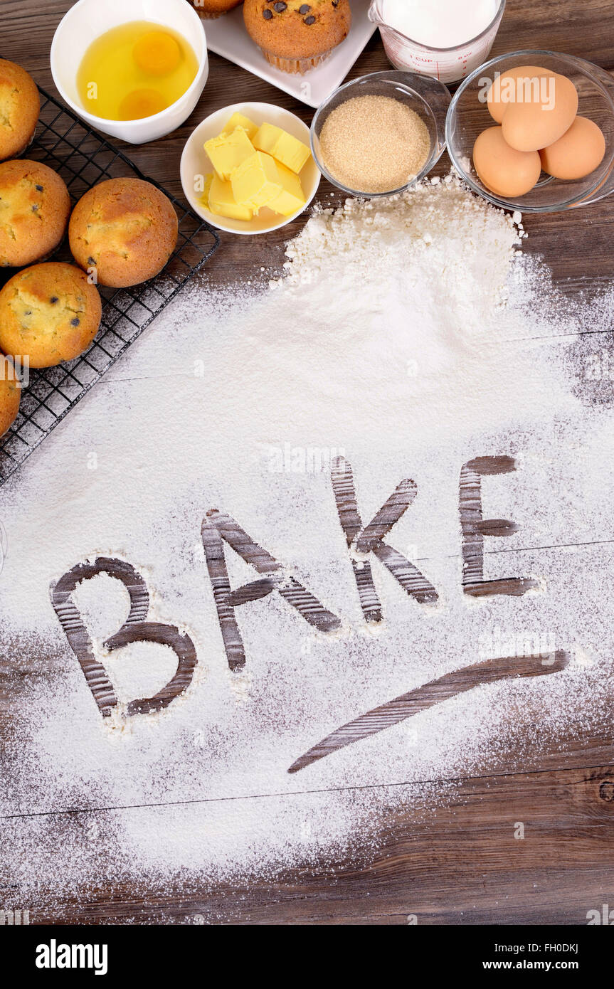 The word Bake written in flour on a dark wood table with freshly baked ...