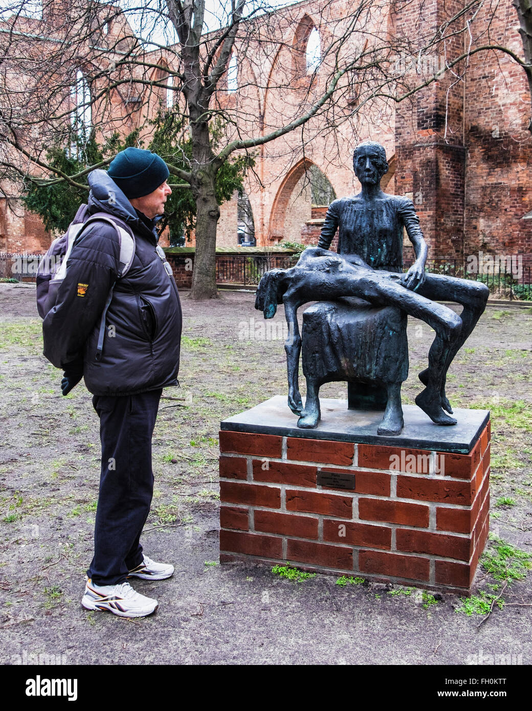 Senior man looking at Bronze 'Pieta' sculpture by Jürgen Pansby at ruin ...