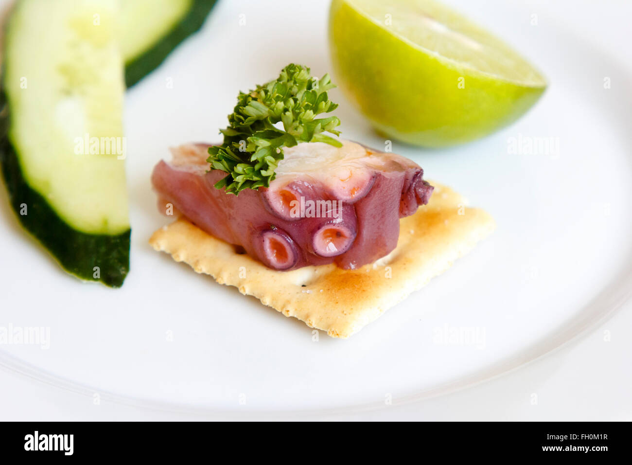 Delicious octopus appetizer on a salty cracker with mexican lime and ...