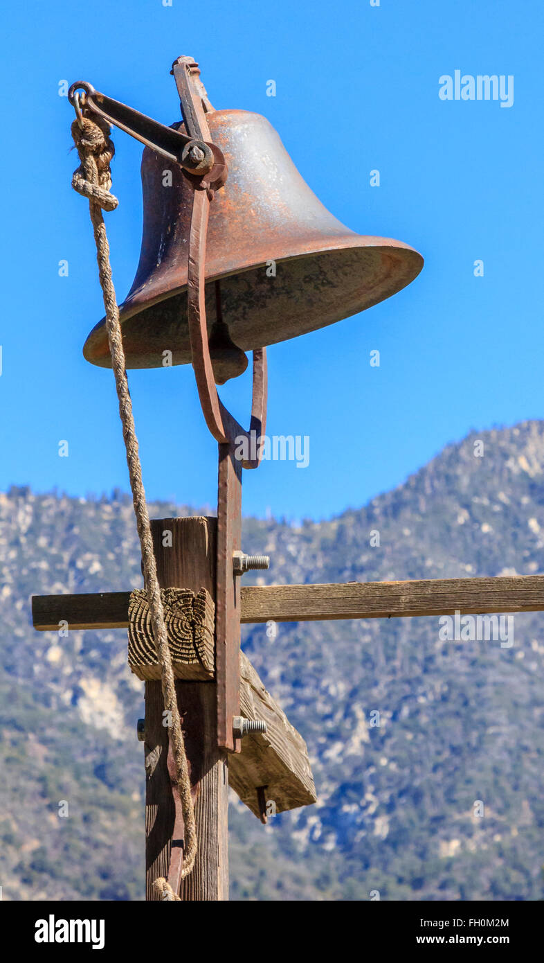 A rusted bell on a wood frame in a farm overlooking the mountains Stock ...