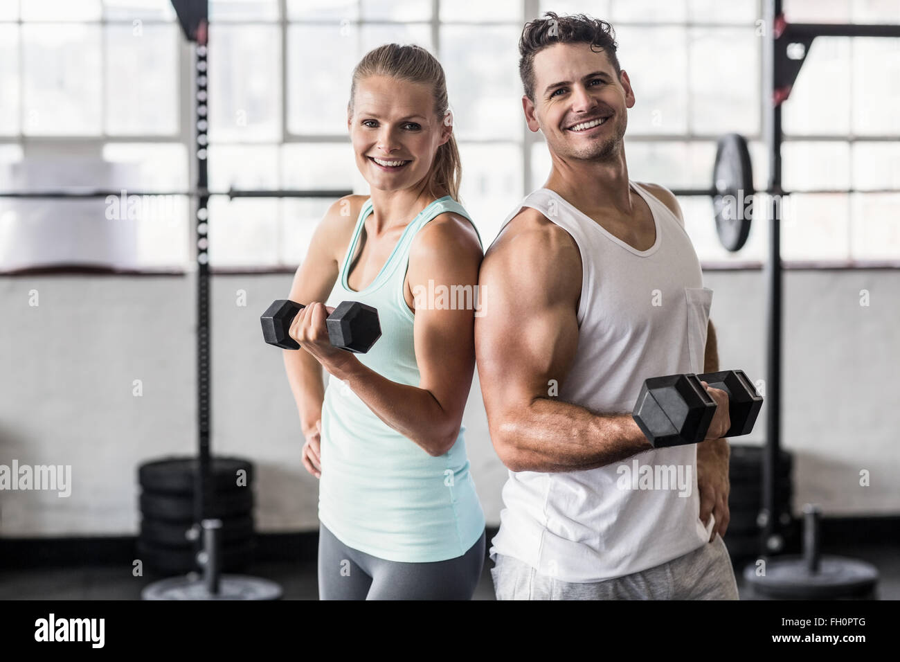Back to back couple exercising with dumbbells Stock Photo - Alamy