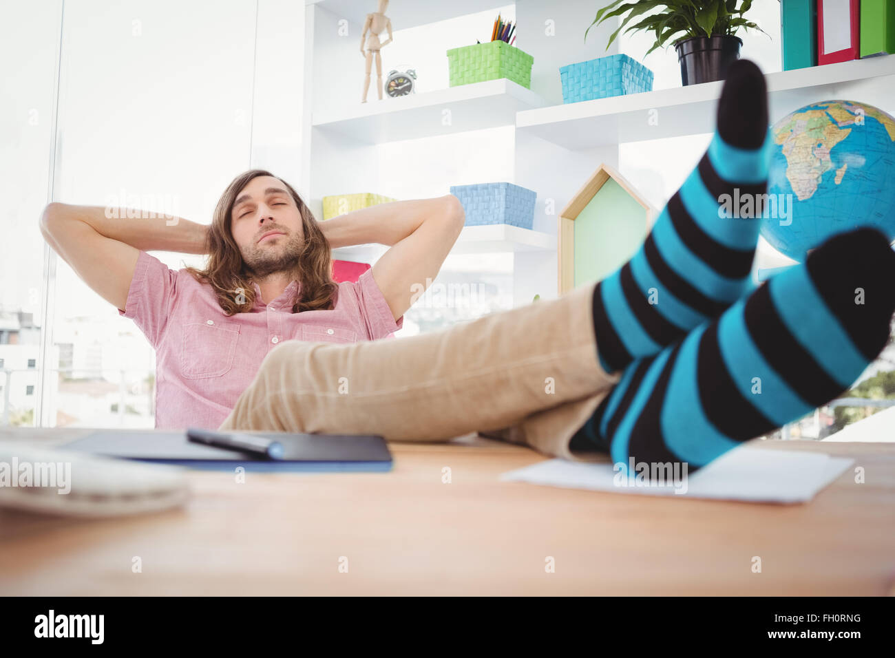 Hipster resting with legs on desk in office Stock Photo - Alamy