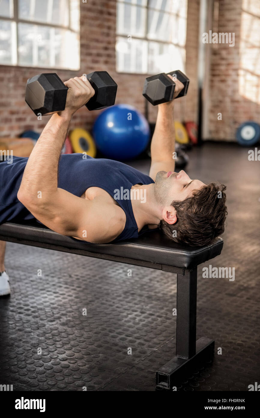 Man lifting dumbbells lying on exercise bench Stock Photo - Alamy