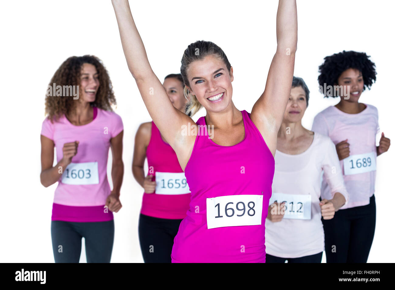 Portrait of smiling winner athlete with arms raised and others running ...
