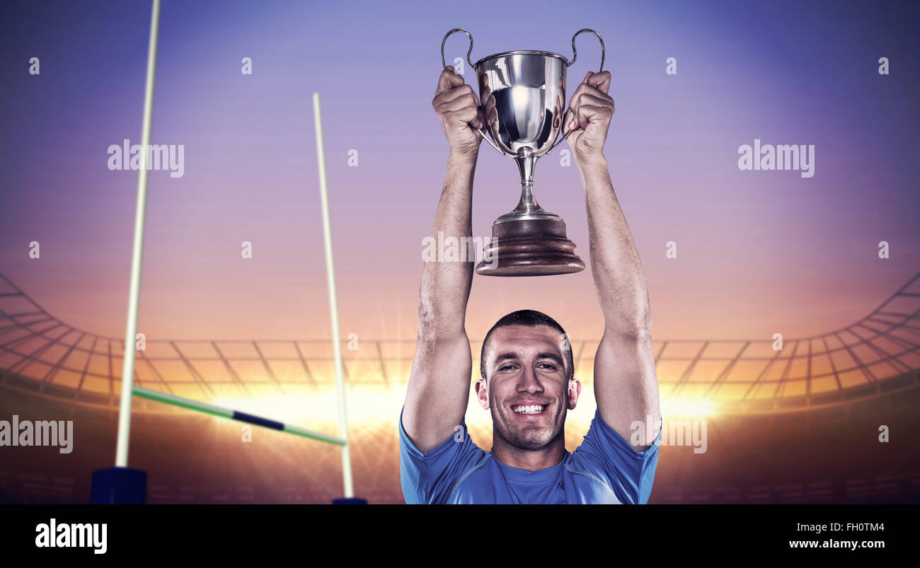 Composite image of portrait of smiling rugby player holding trophy ...