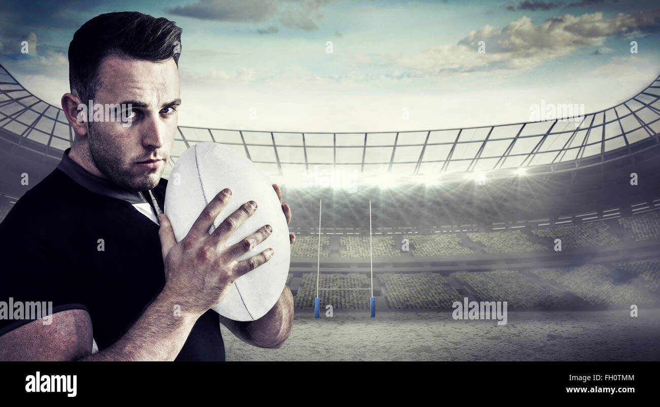 Composite image of tough rugby player holding ball Stock Photo - Alamy