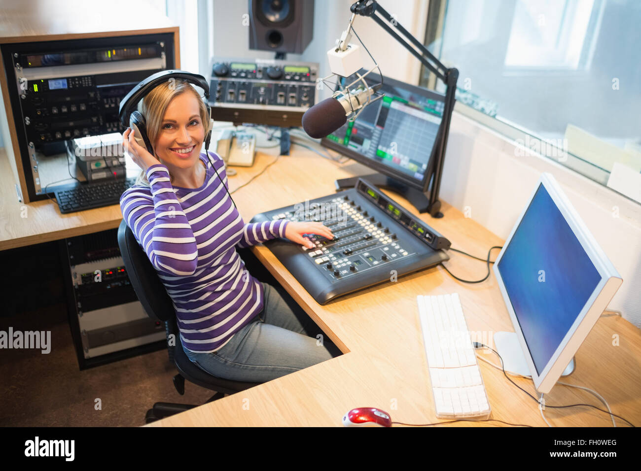 Happy female radio host at sound mixer desk in studio Stock Photo - Alamy