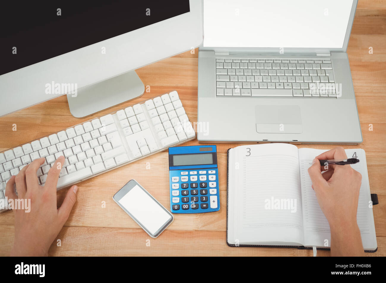 Businessman writing on diary using computer at desk Stock Photo - Alamy