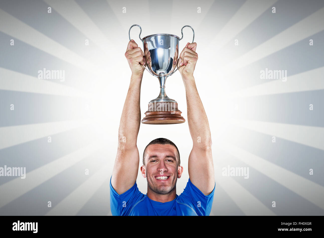 Composite image of portrait of smiling rugby player holding trophy ...