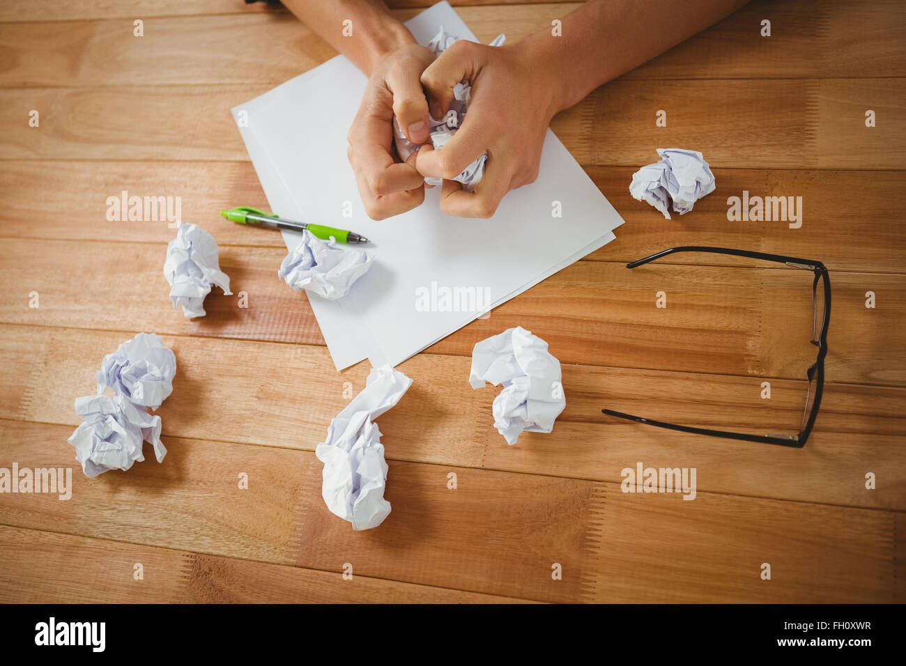 Man crushing paper while sitting at desk in office Stock Photo - Alamy