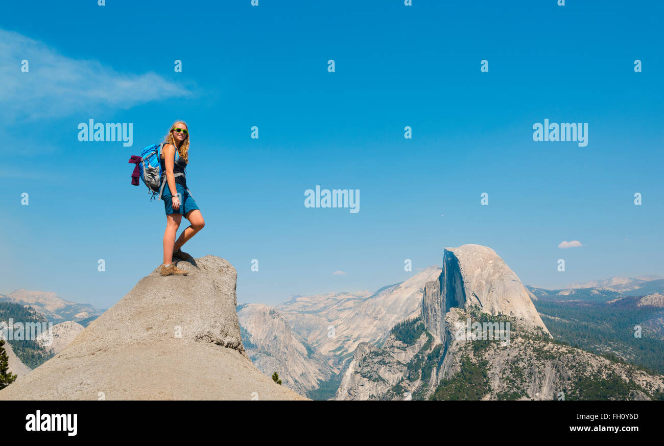 Hiker standing on a cliff, behind Half Dome, view from Glacier Point ...