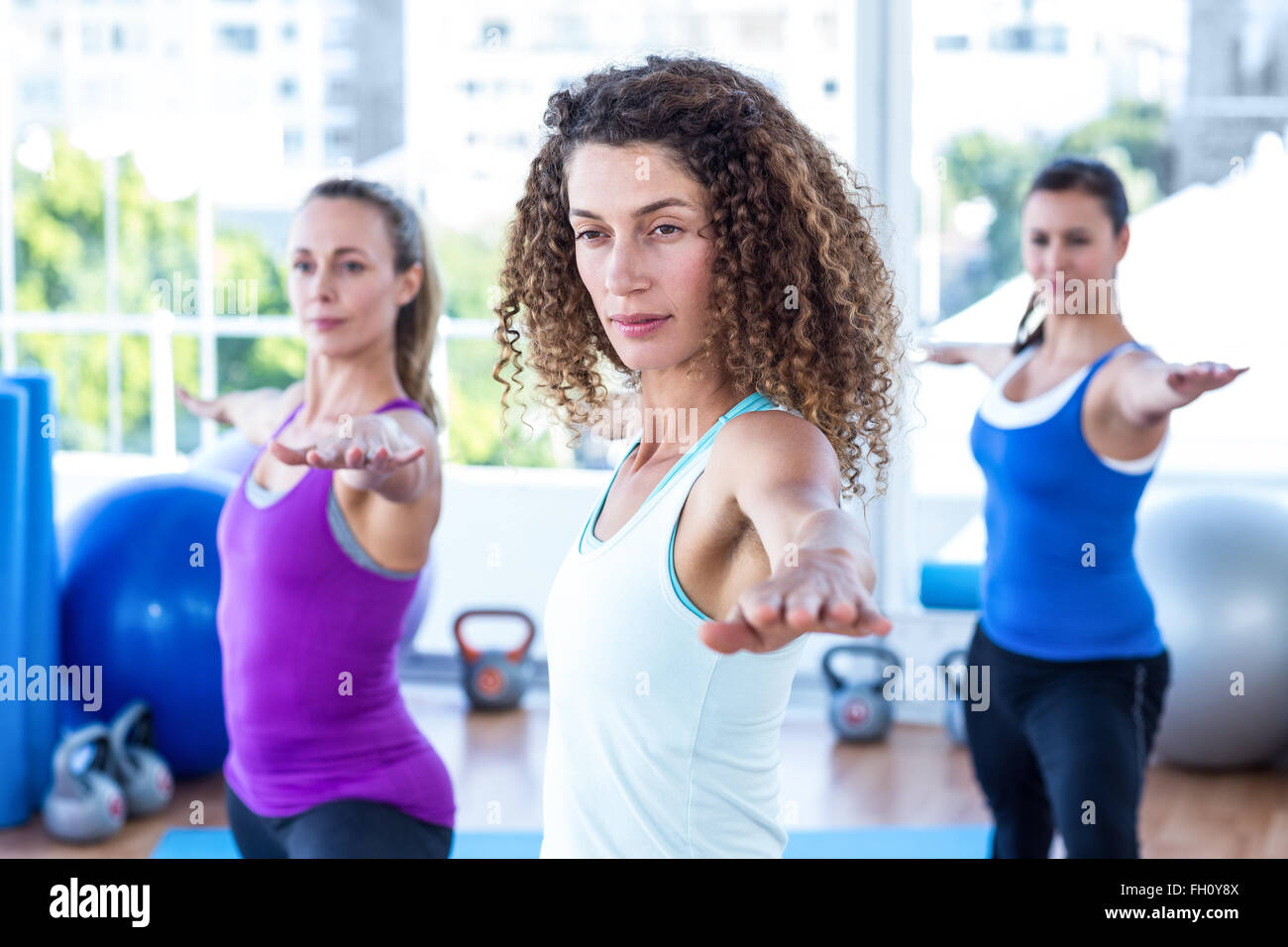 Focused women doing warrior II pose Stock Photo - Alamy