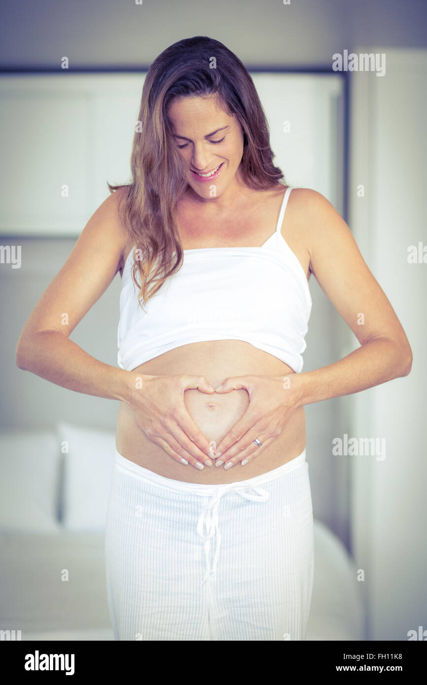 Happy woman making heart on belly Stock Photo - Alamy