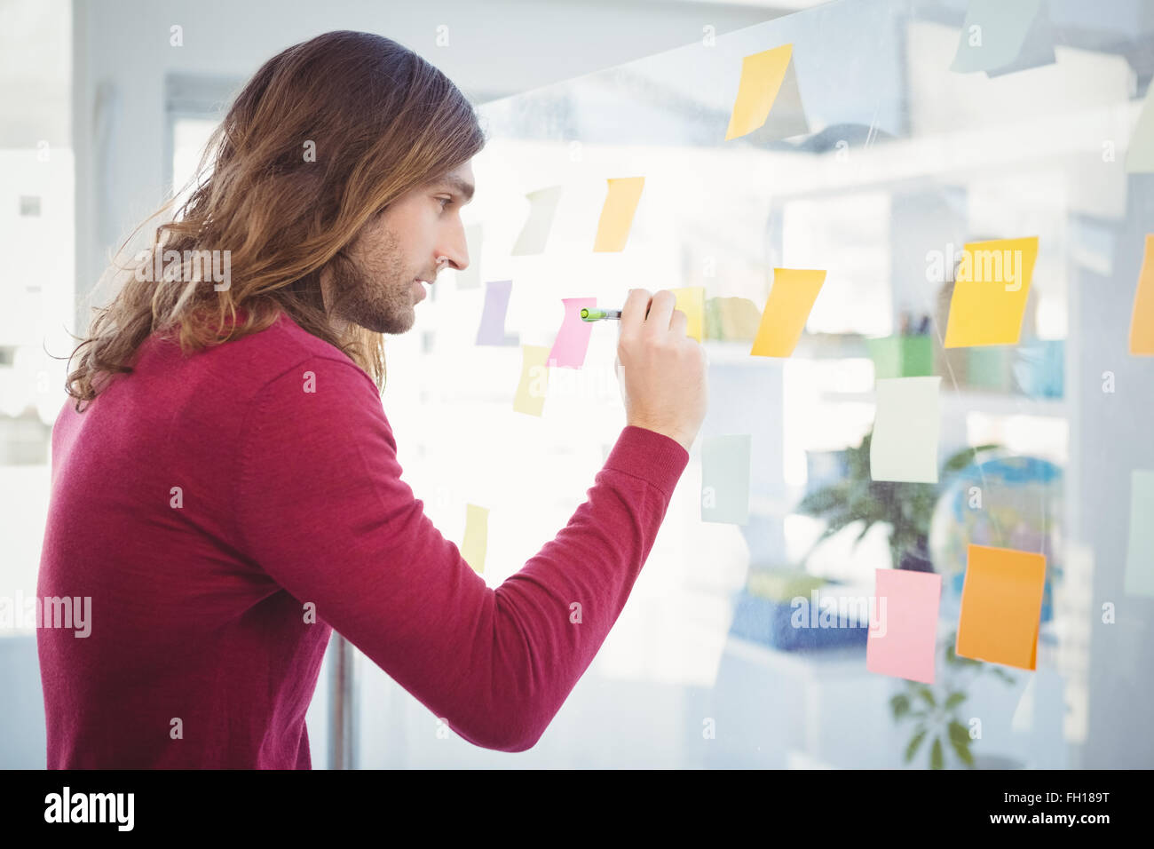 Hipster writing on sticky note stuck on glass Stock Photo - Alamy