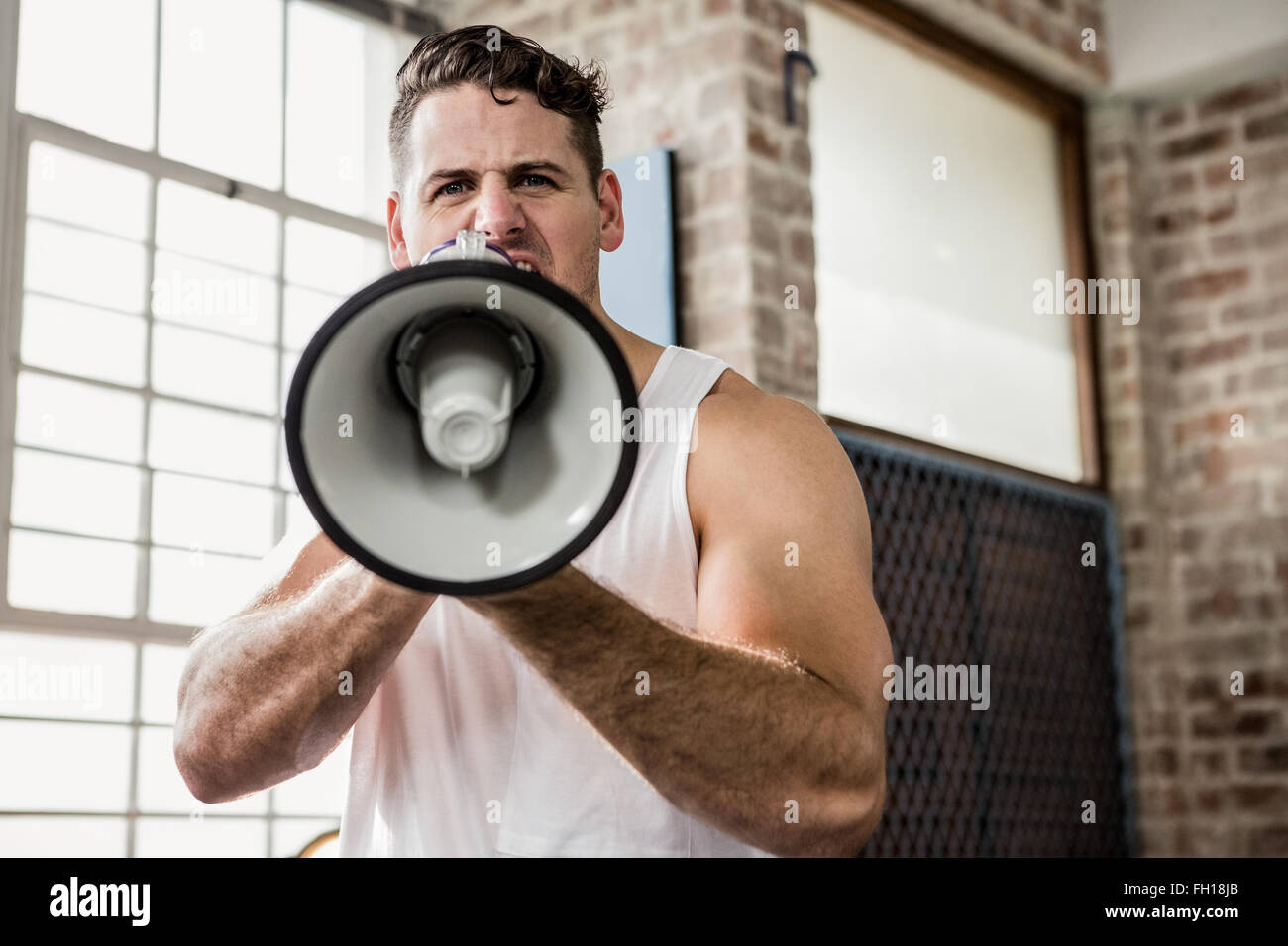 Portrait of muscular man talking through megaphone Stock Photo - Alamy