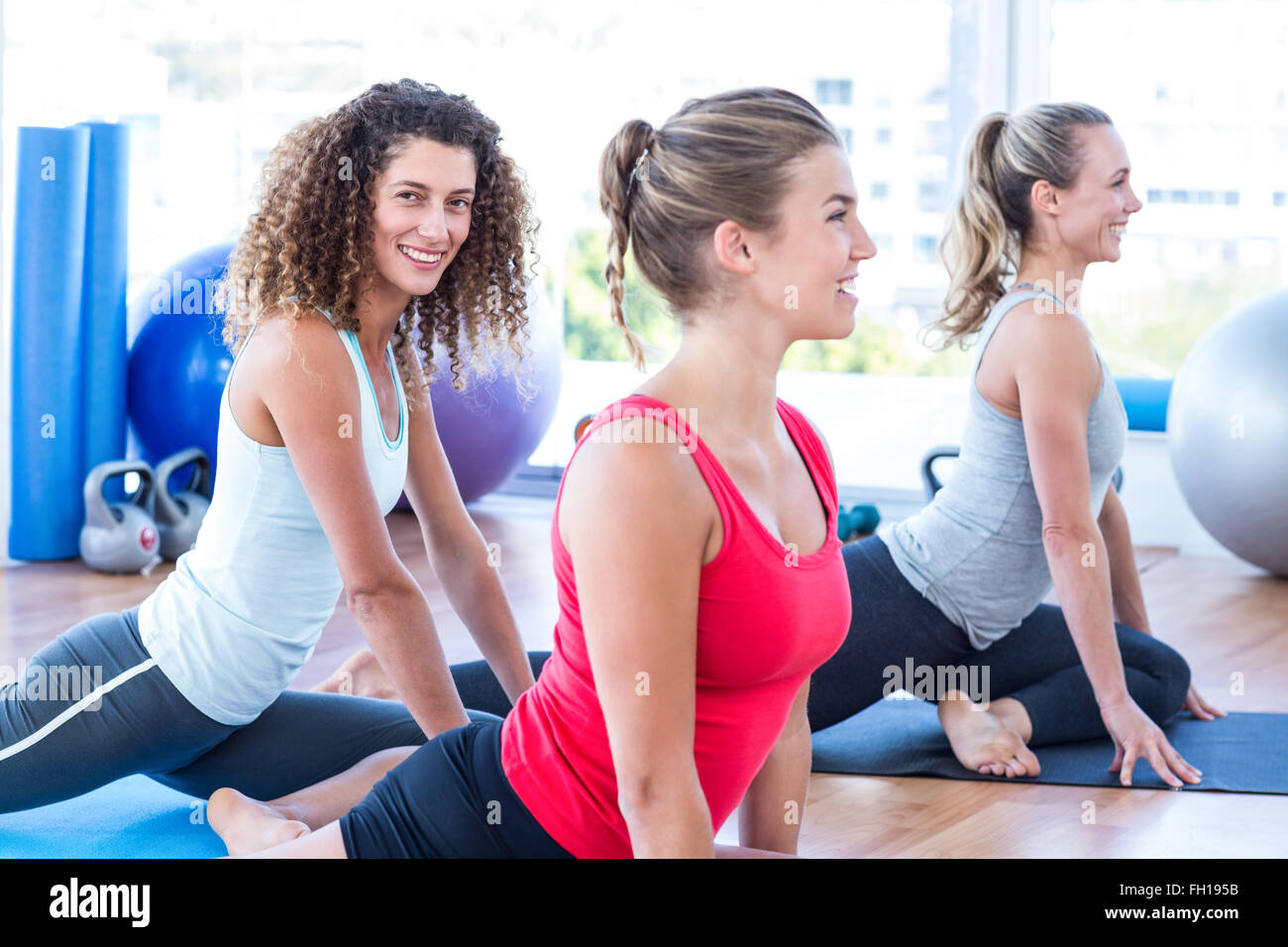 Women smiling while doing pigeon posture Stock Photo - Alamy