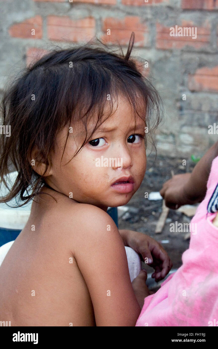 A young girl living in poverty sits outside home in Kampong Cham ...